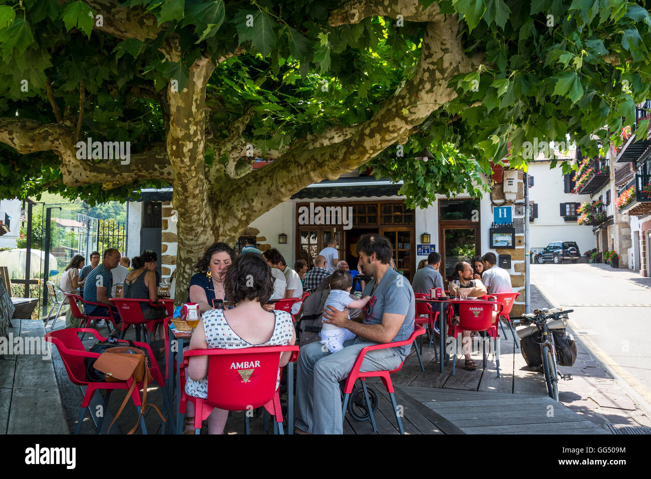 People sitting in an outdoor cafe shaded by a plane tree, Bera village ...