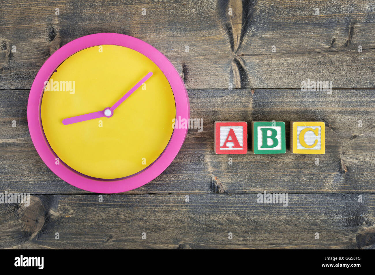 Clock and word ABC on wooden table Stock Photo - Alamy