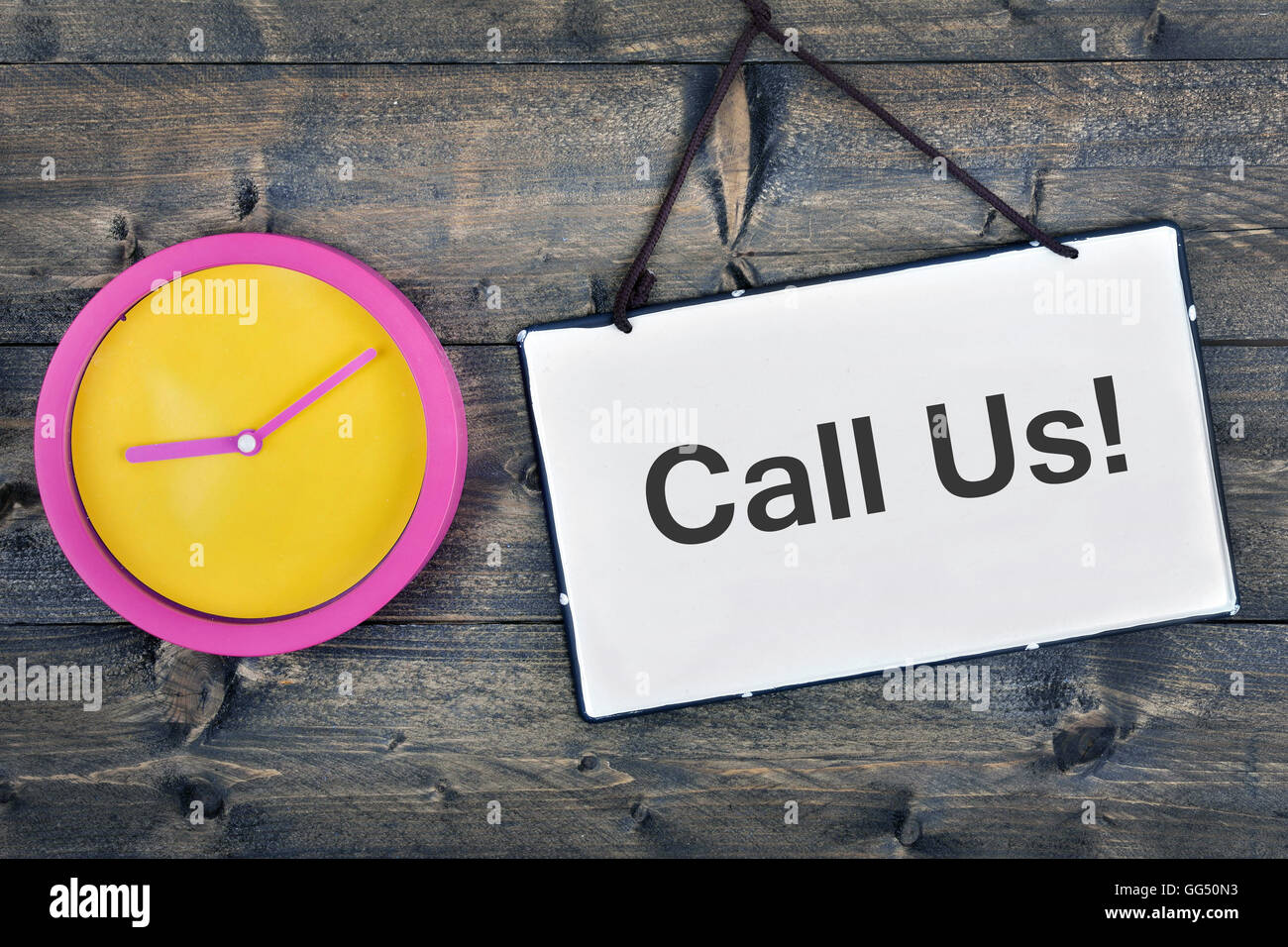 Call us sign and clock on wooden table Stock Photo - Alamy