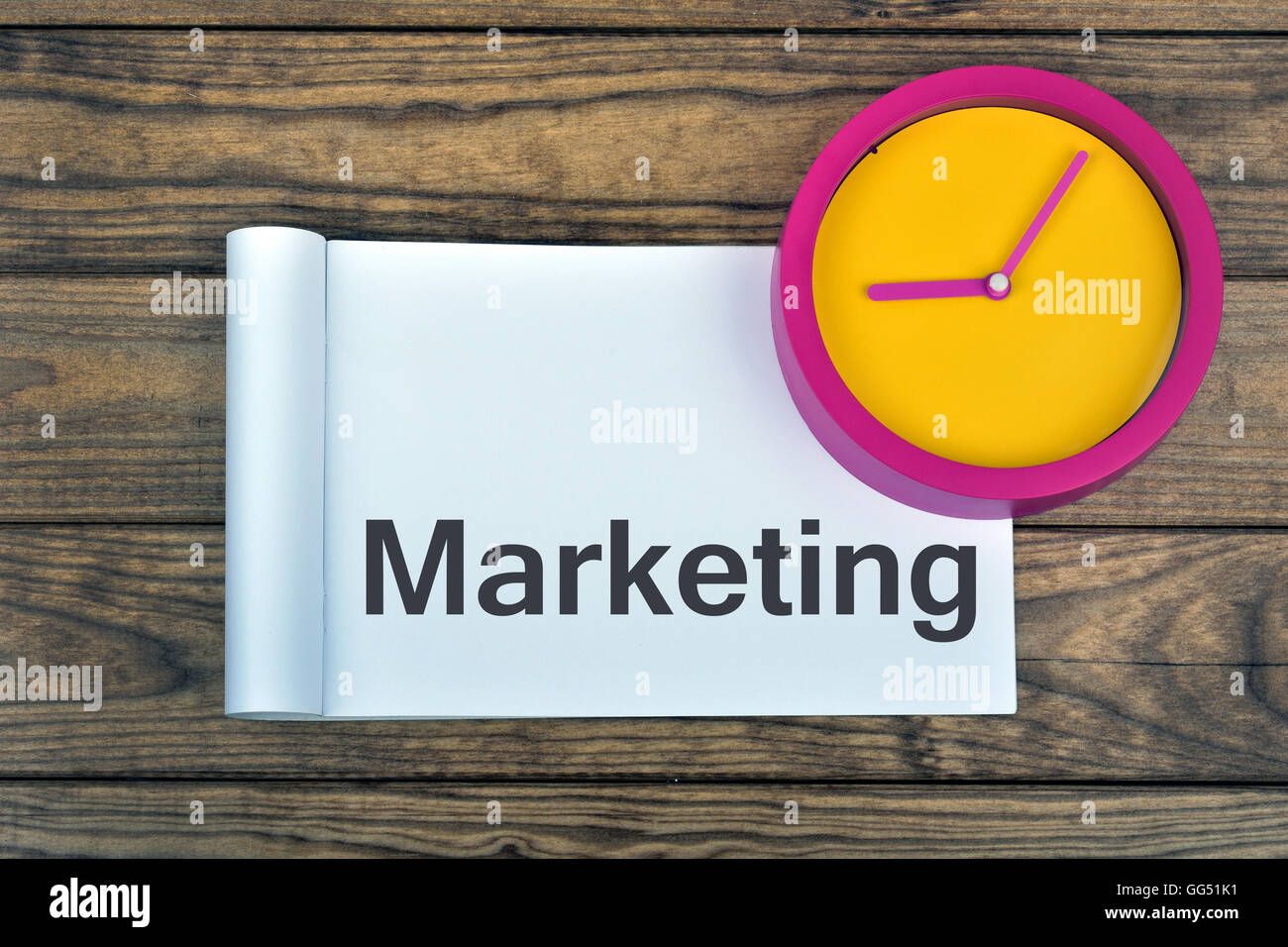 Clock and word Marketing on wooden table Stock Photo - Alamy