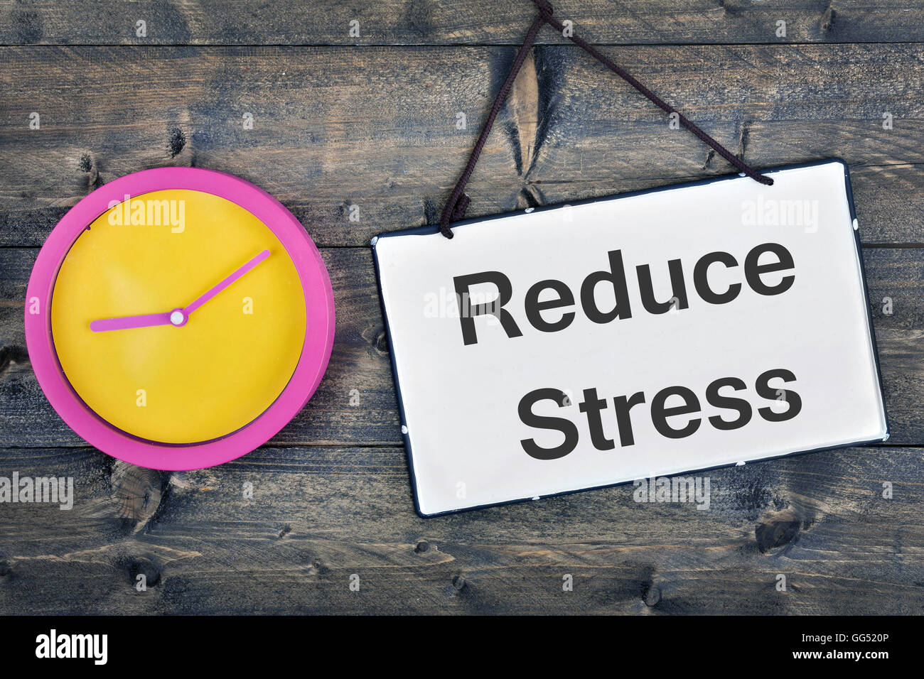 Reduce Stress sign and clock on wooden table Stock Photo - Alamy