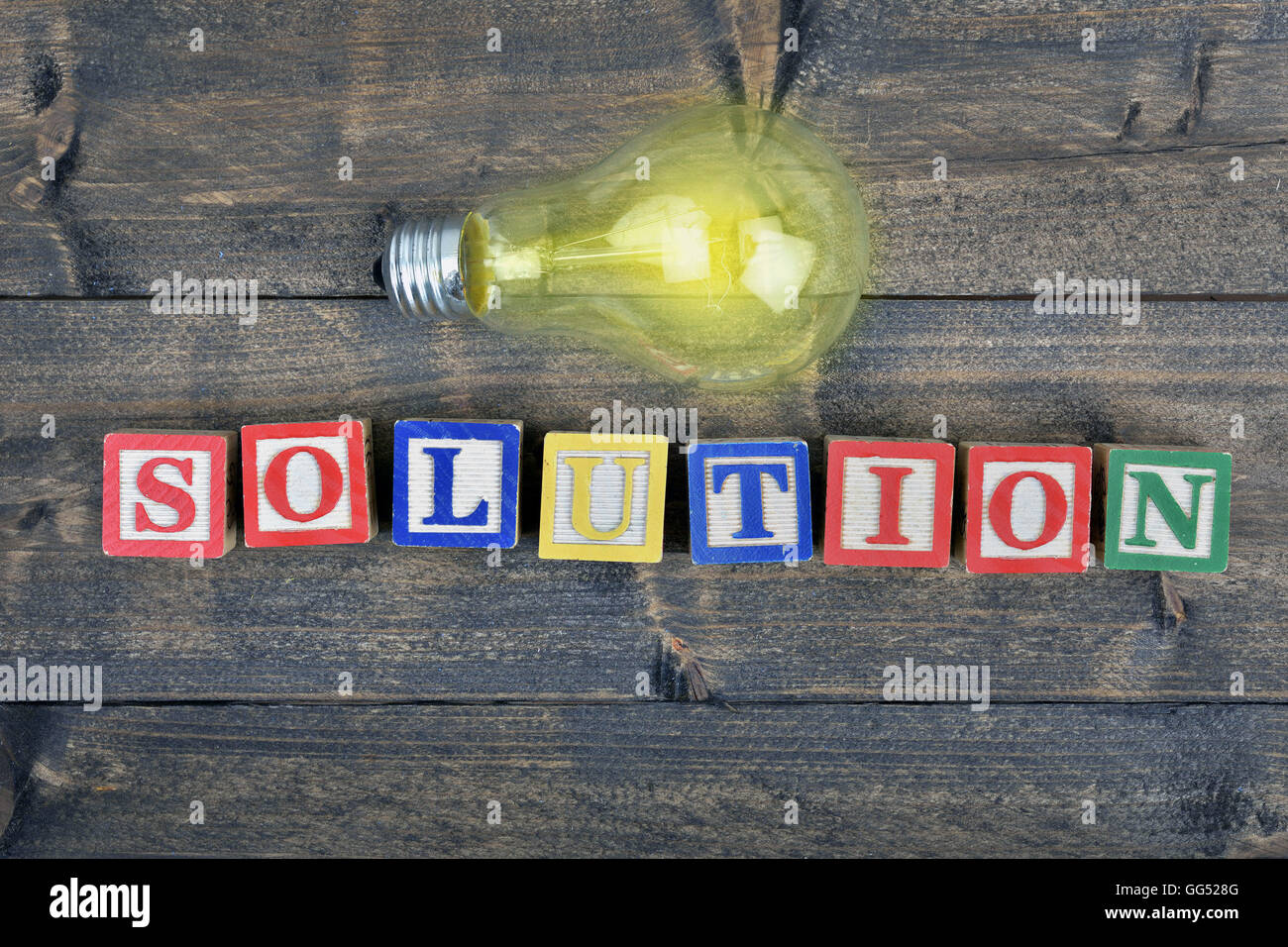 Bulb and word Solutions on wooden table Stock Photo - Alamy