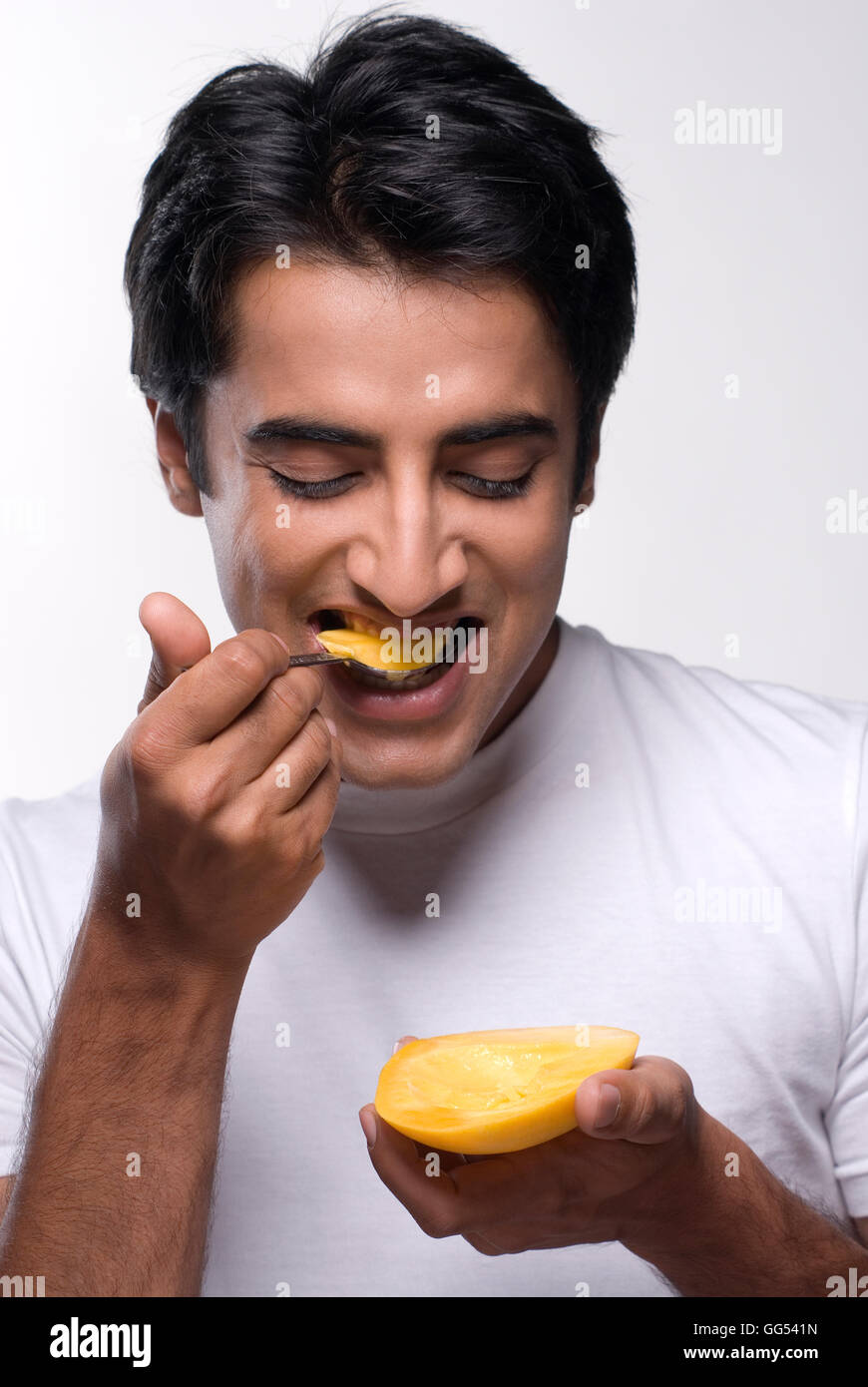 Man eating a mango Stock Photo - Alamy