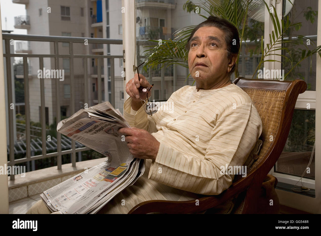 Old man with a newspaper thinking Stock Photo - Alamy