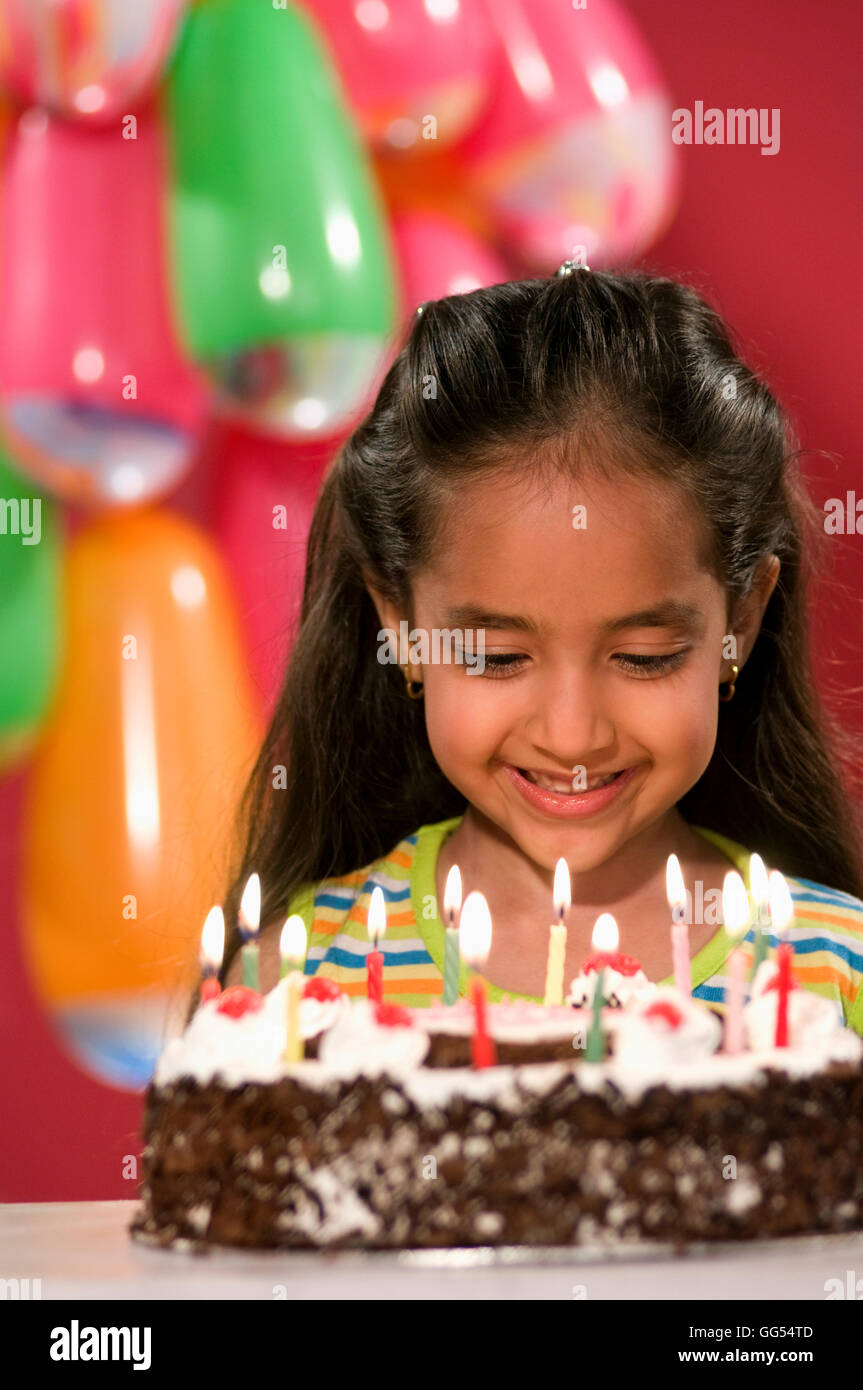 A girl looking at her birthday cake Stock Photo - Alamy