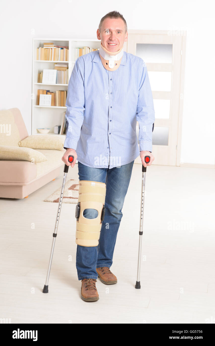 Man with leg in neck brace, knee cages and crutches for stabilization ...