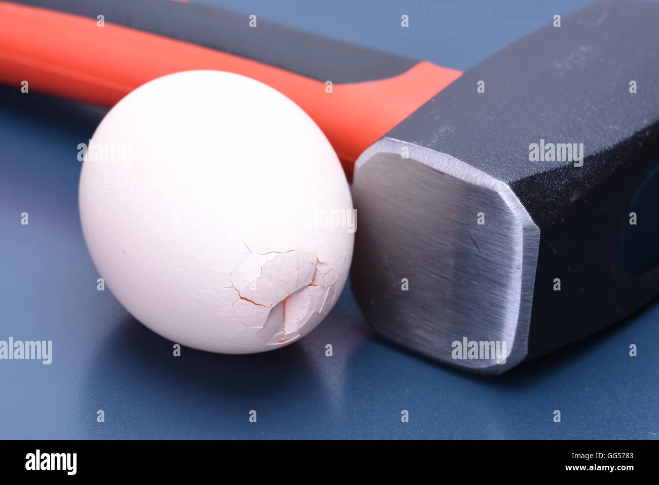 Heavy hammer and broken egg Stock Photo - Alamy