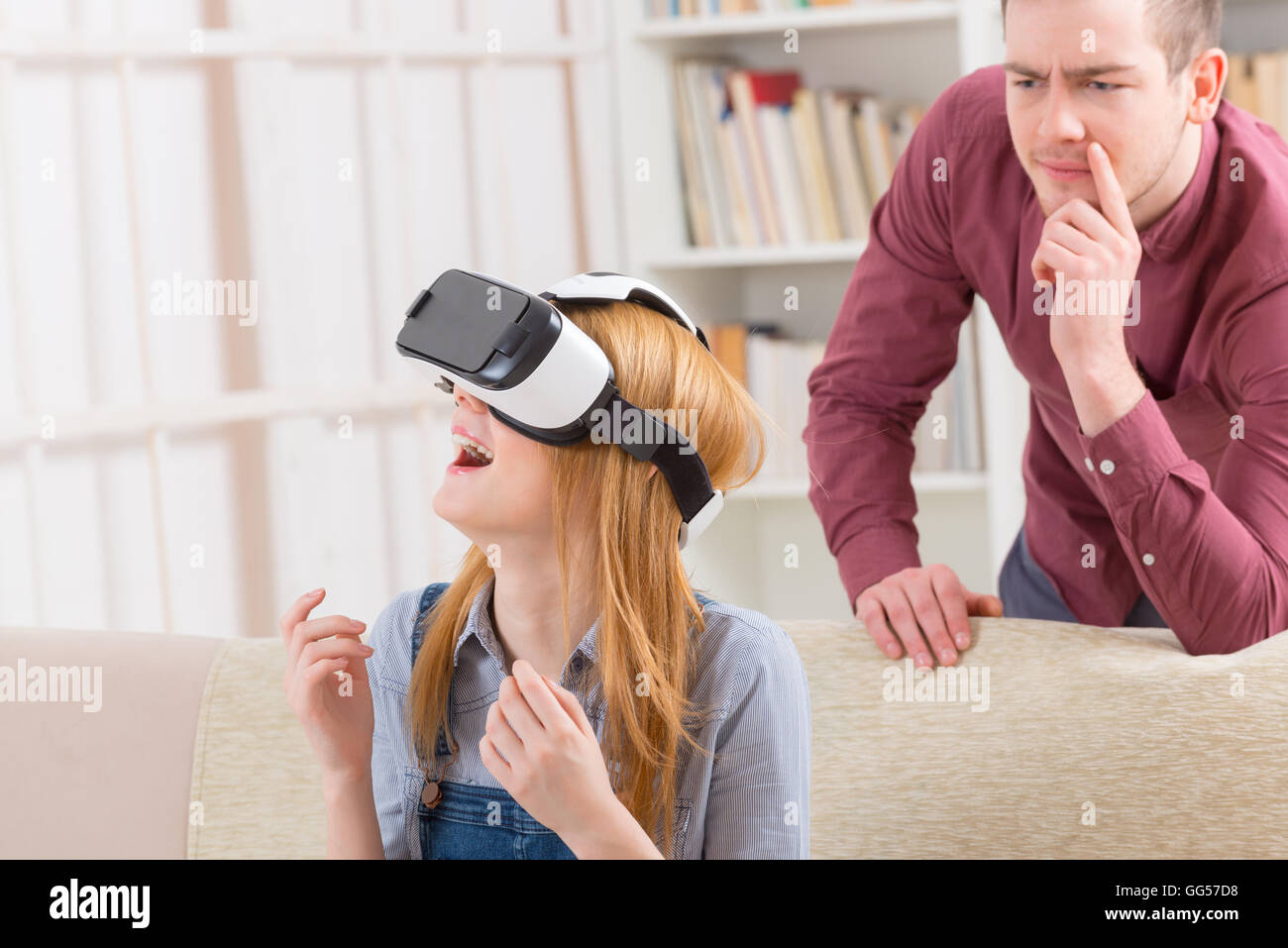 Young woman using virtual reality headset and her boyfriend or partner ...
