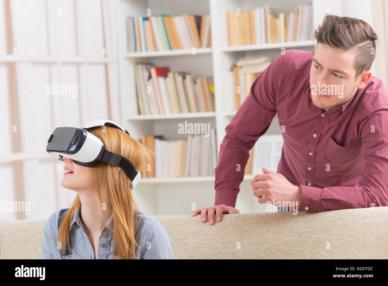 Young woman using virtual reality headset and her boyfriend or partner ...
