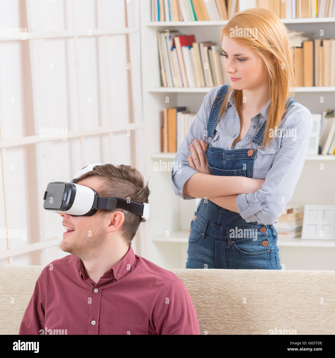 Young man using virtual reality headset and his girlfriend or partner ...