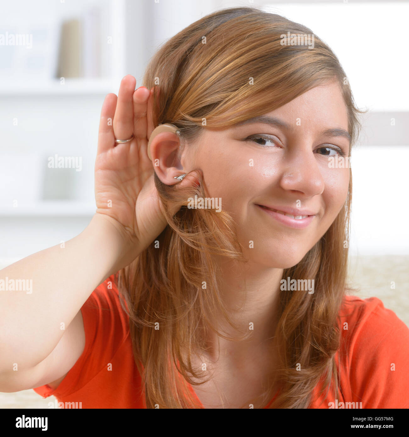 Young, smiling woman wearing deaf aid Stock Photo - Alamy