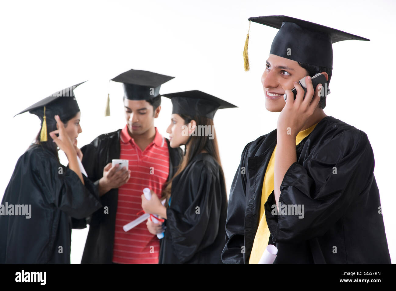 Smiling graduate student answering mobile phone with friends discussing ...
