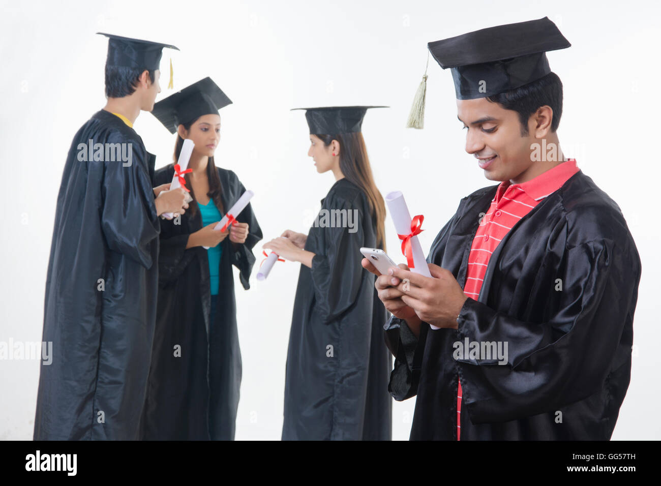 Male graduate student using smart phone with friends discussing against ...