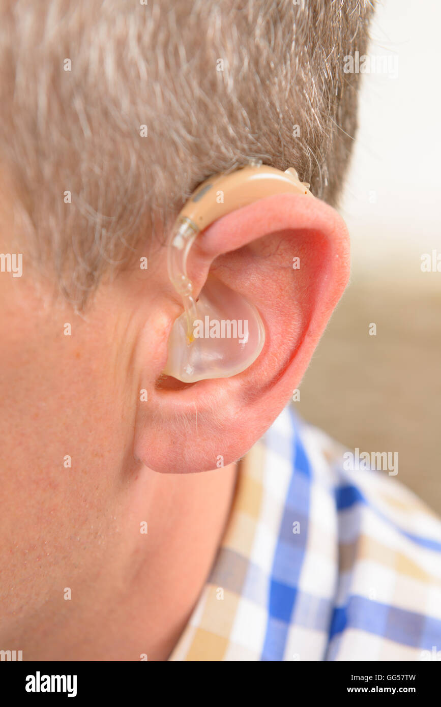Man showing deaf aid in ear Stock Photo - Alamy