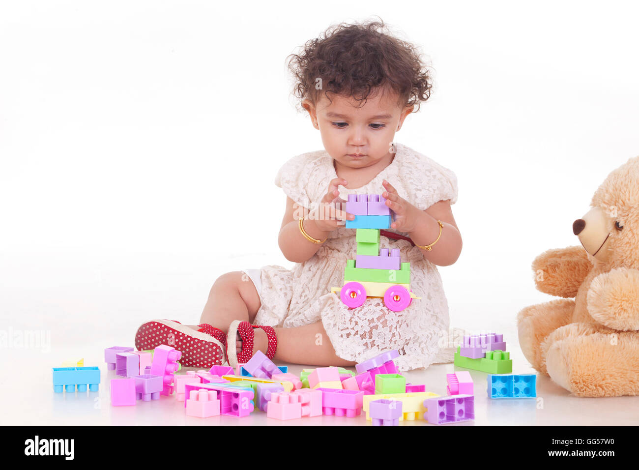 Full length of cute girl playing with blocks against white background ...