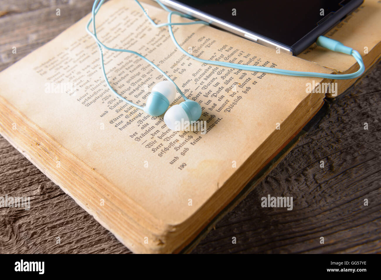 Headphones and mobile phone on the old book. Concept of listening to ...