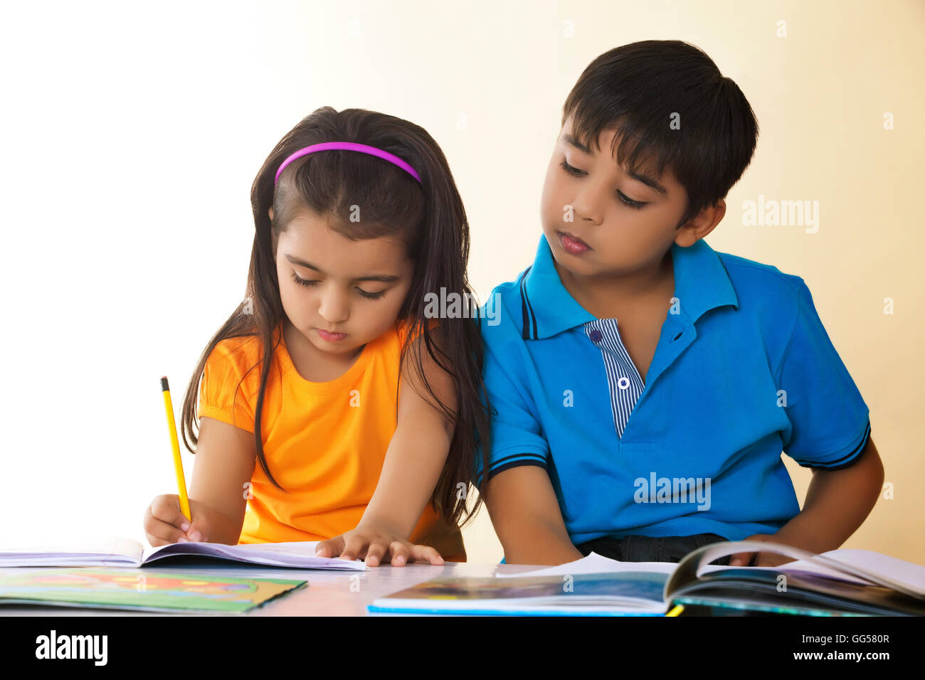 Cute children studying at table against colored background Stock Photo ...