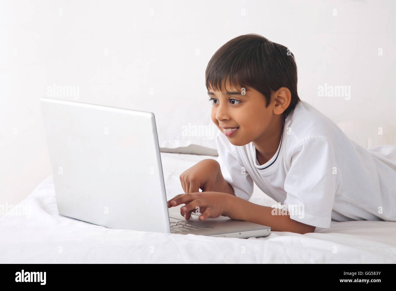 Boy using laptop in bed Stock Photo - Alamy