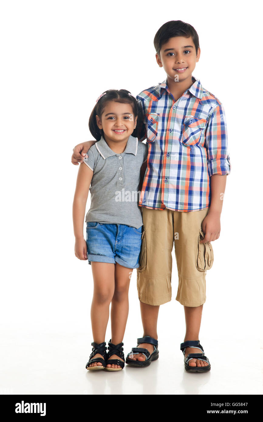 Full length portrait of smiling siblings standing against white ...