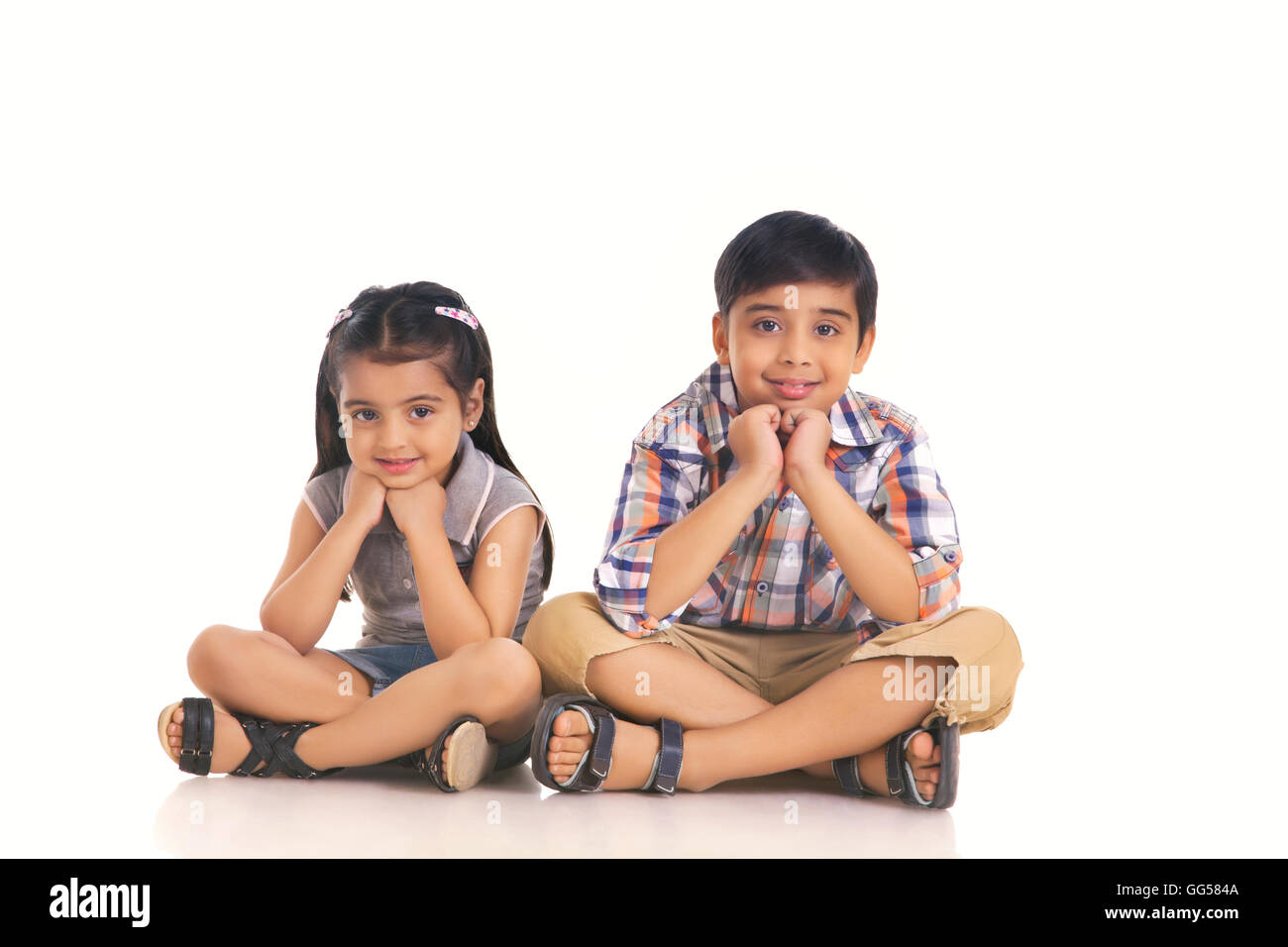 Full length portrait of smiling siblings sitting over white background ...