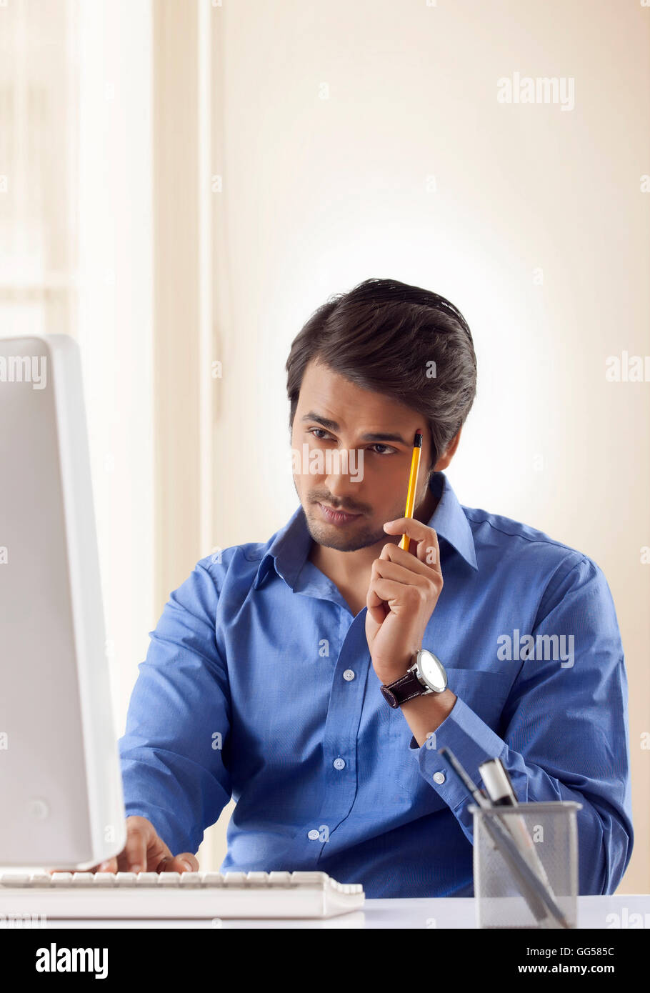 Thoughtful young businessman using computer at office desk Stock Photo - Alamy