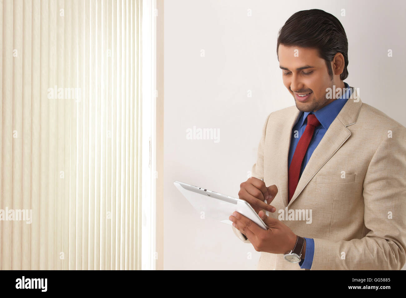 Indian businessman using digital tablet by window blinds Stock Photo ...