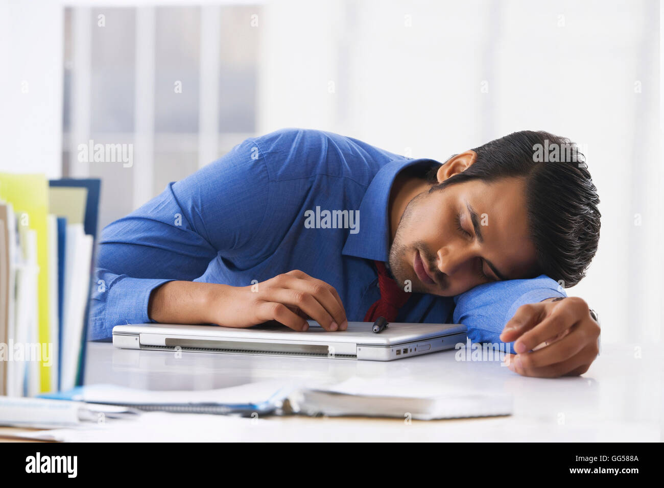 Young Indian businessman sleeping on laptop at office desk Stock Photo ...