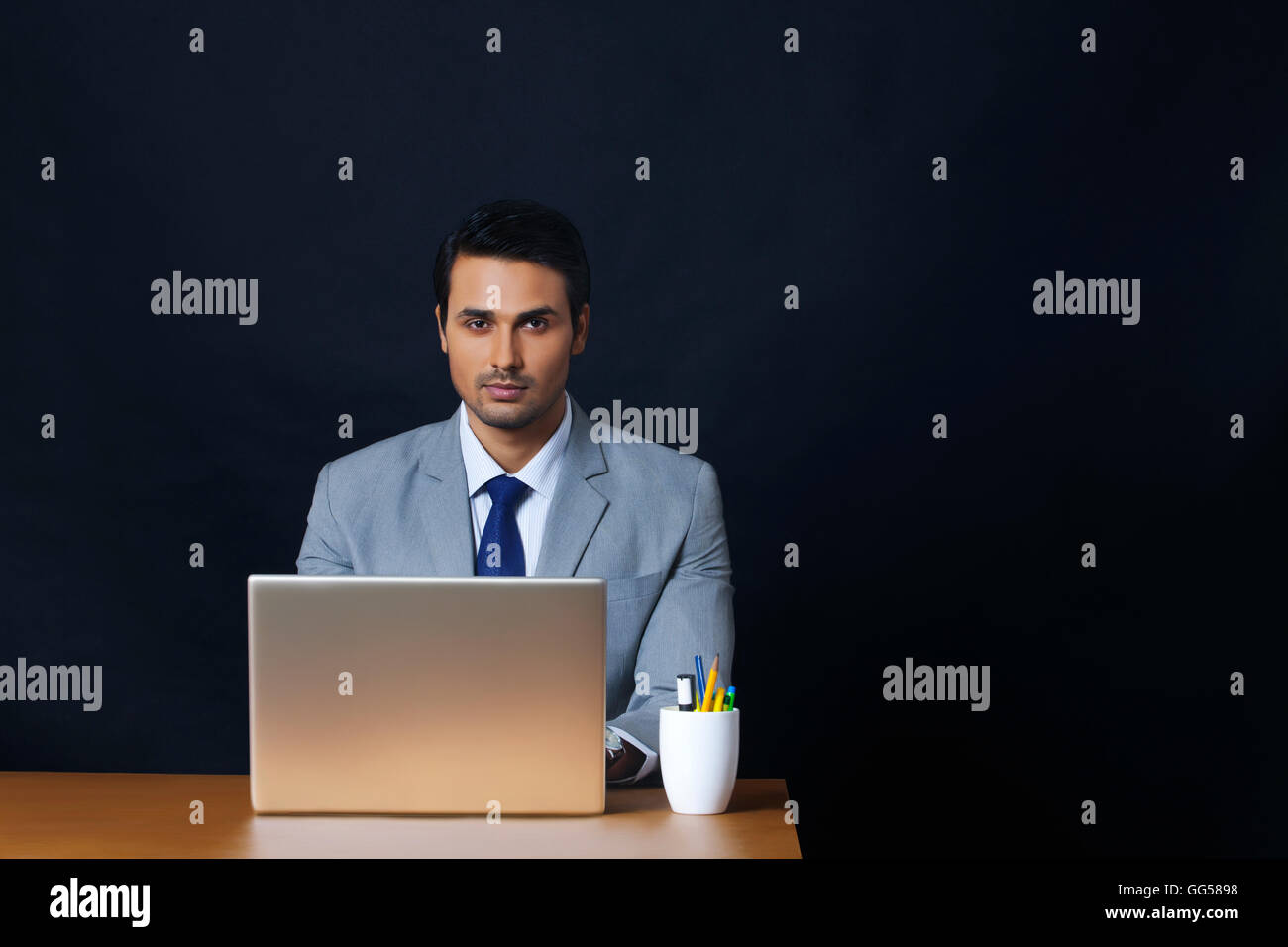 Portrait of handsome young businessman using laptop in office Stock ...