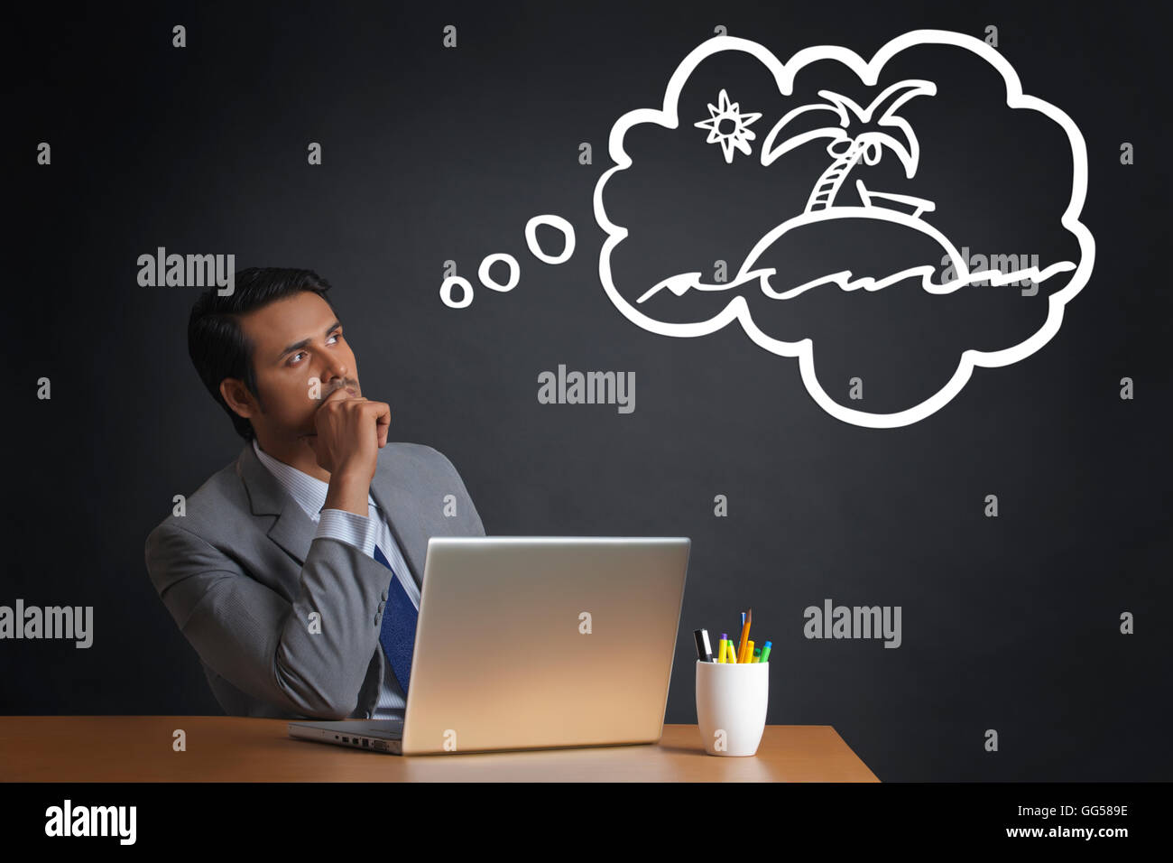 Young Indian businessman thinking of vacation while at work Stock Photo ...