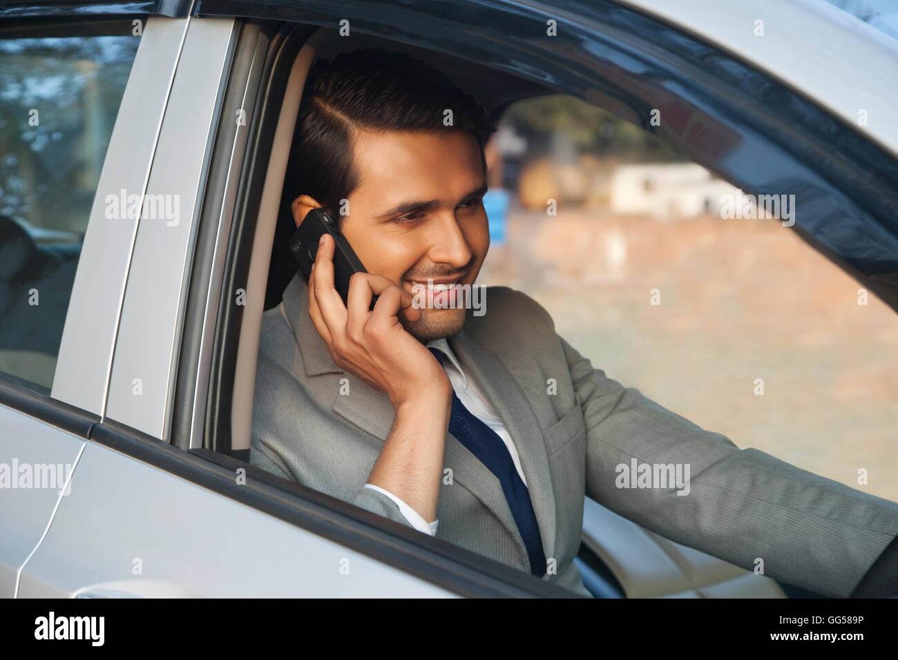 Happy young businessman on call while driving car Stock Photo - Alamy