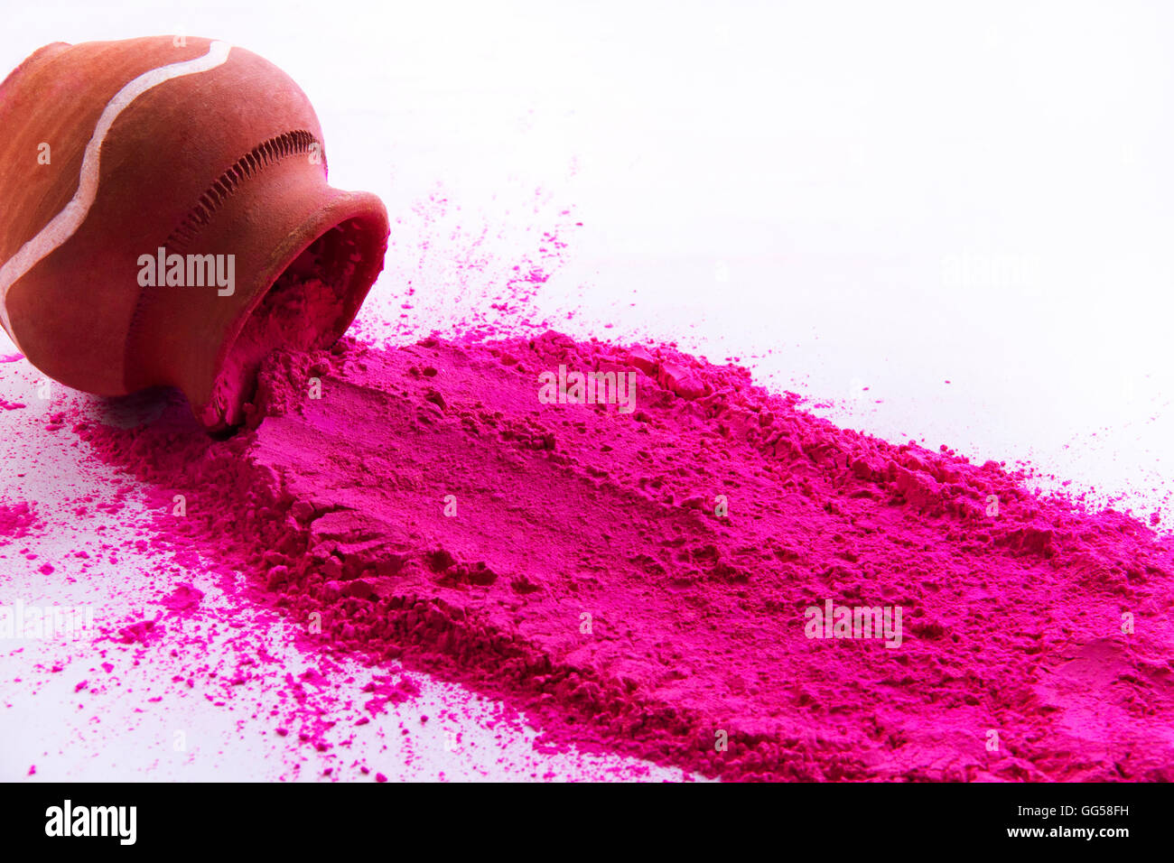 Pink Holi color powder spilt from pot over white background Stock Photo ...