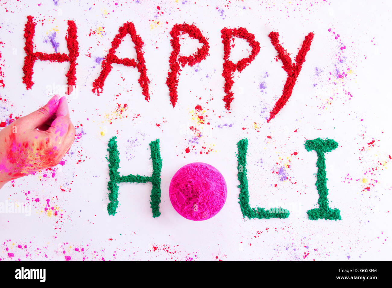 Directly above shot of hand writing HAPPY Holi with gulal over white ...