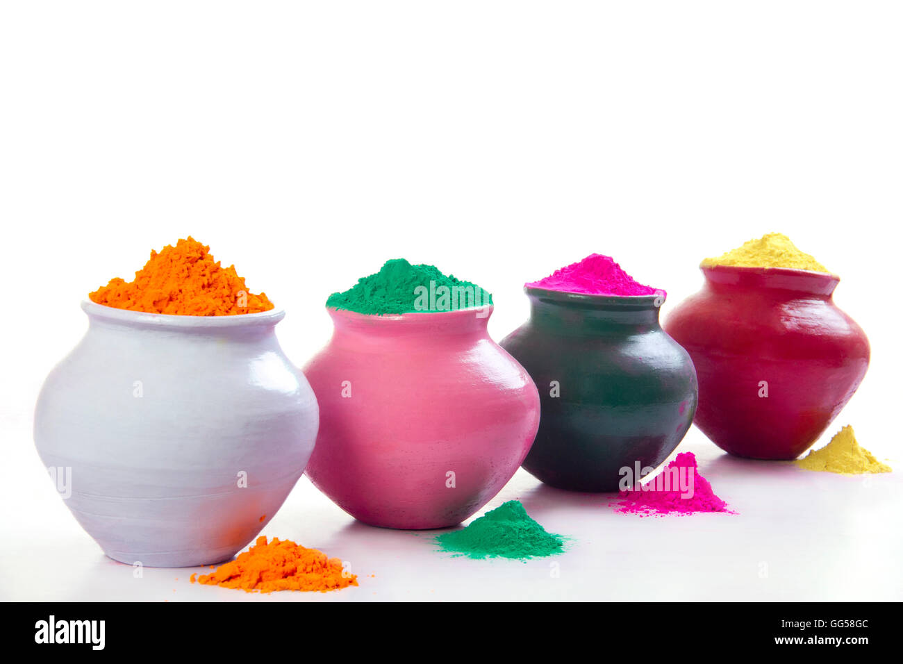 Row of pots filled with colorful Holi powder over white background ...