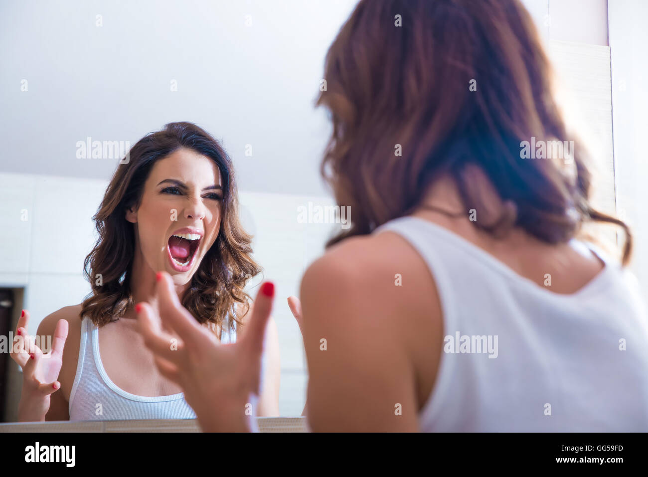 A beautiful young woman screaming in the mirror in the bathroom Stock ...