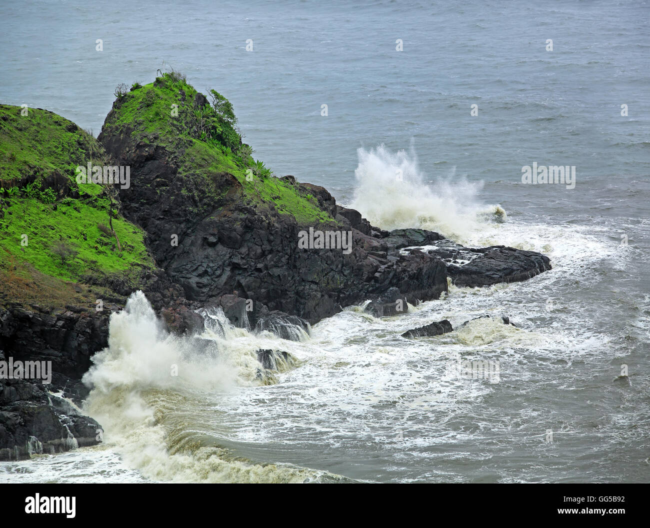 Ocean waves breaking and splashing on rocky cliff during monsoon season ...