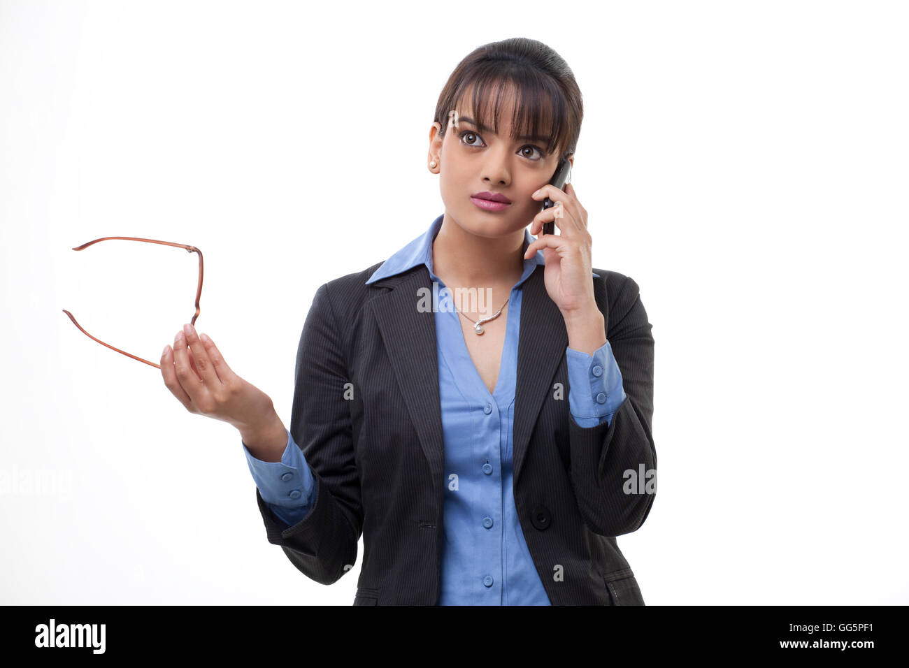 Confident young business woman holding glasses while using cell phone on white background Stock ...