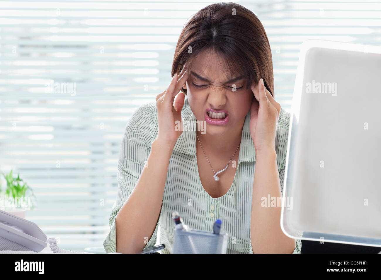 Young female executive with severe headache at workplace Stock Photo ...