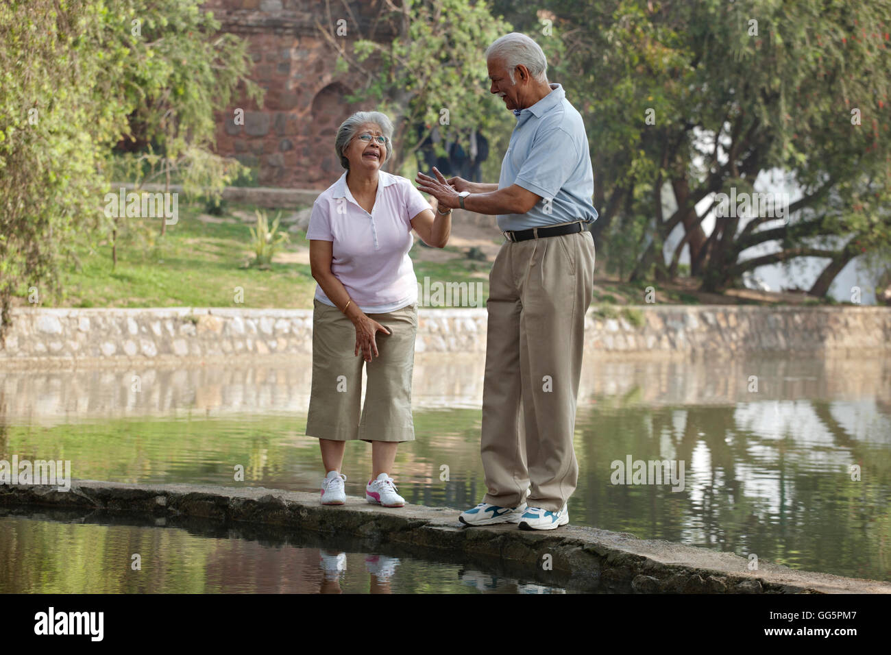 Mature woman afraid of walking on narrow bridge with man at park Stock ...