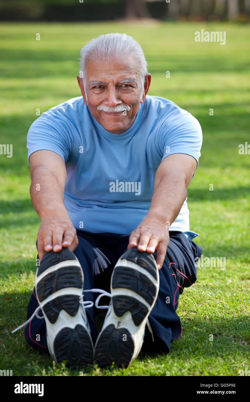 Portrait of smiling man stretching in park Stock Photo - Alamy