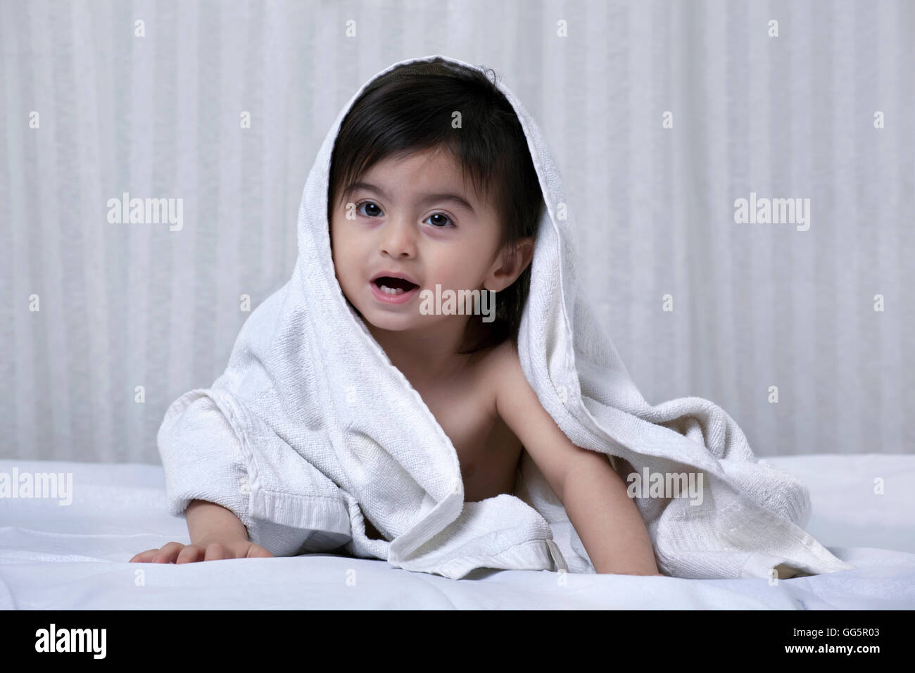 Little boy with a towel around his body on a bed Stock Photo - Alamy
