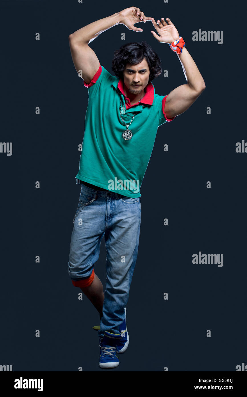 Full length of young Indian man with arms raised against black ...