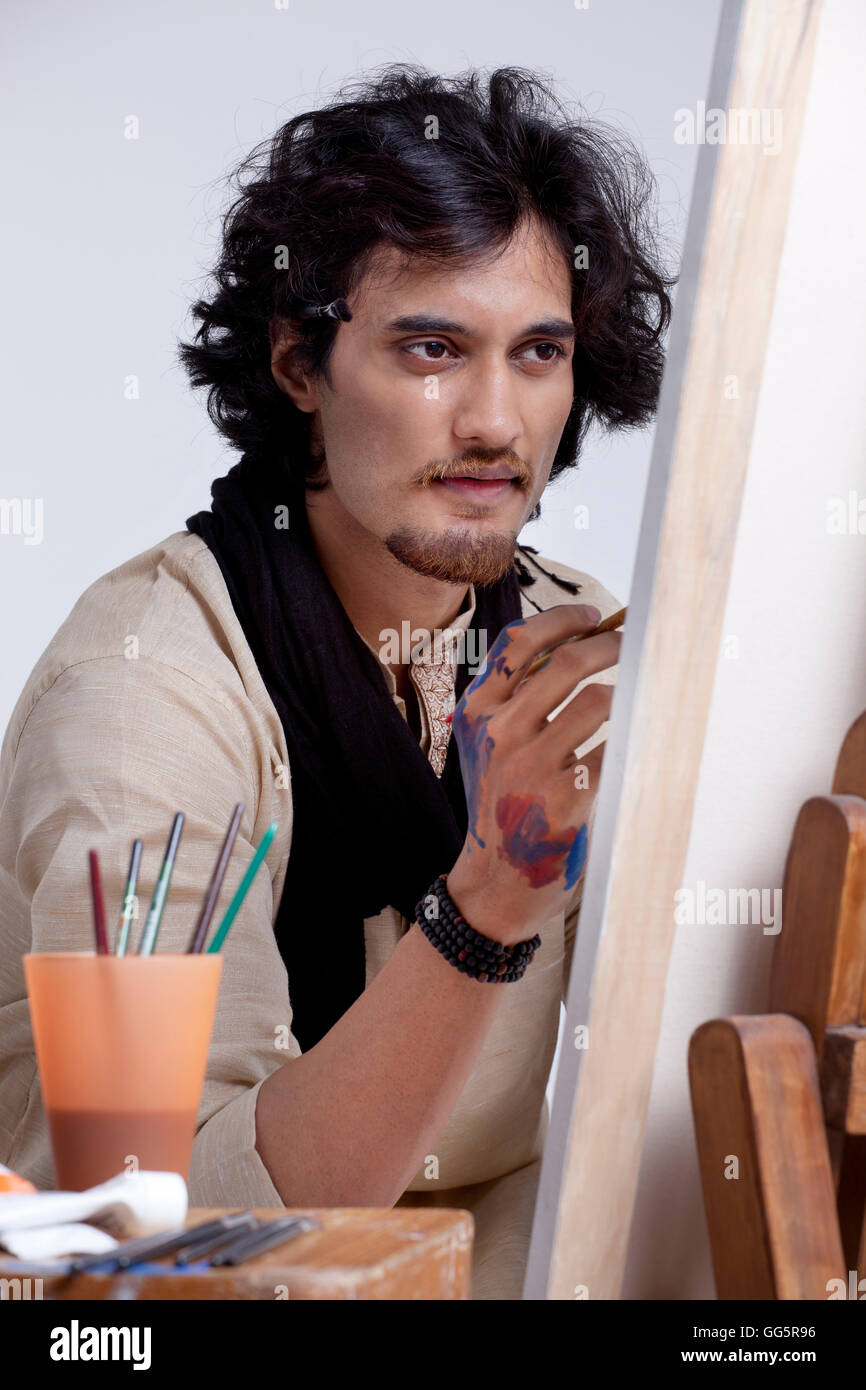 Handsome artist focusing on painting Stock Photo - Alamy