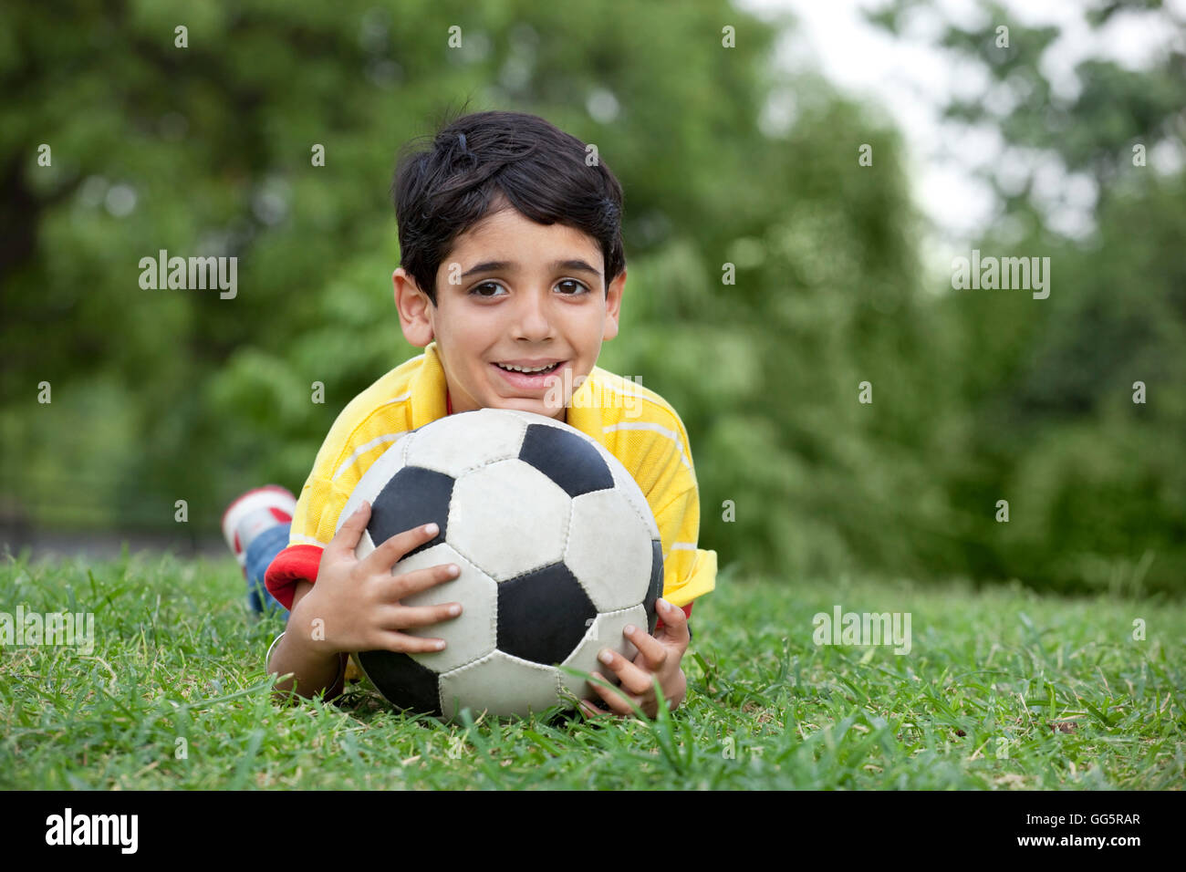 Portrait of young boy lying on grass with ball Stock Photo - Alamy