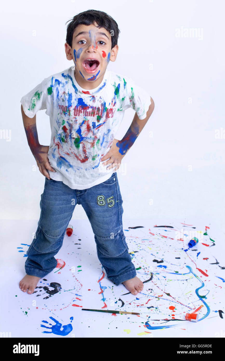 Young mischievous boy shouting with paint all over him against white ...