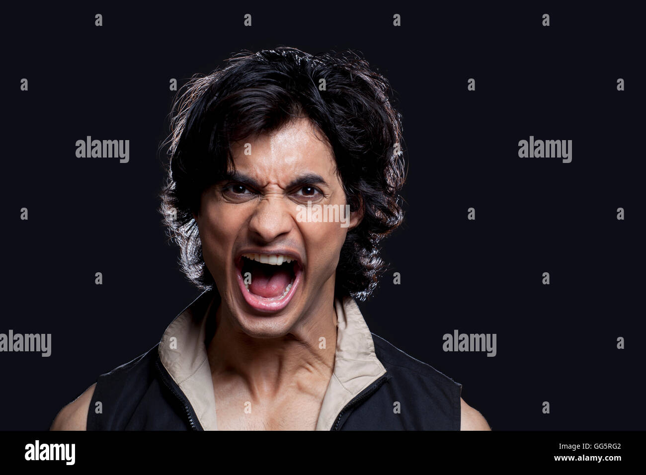 Portrait of young man screaming against black background Stock Photo ...