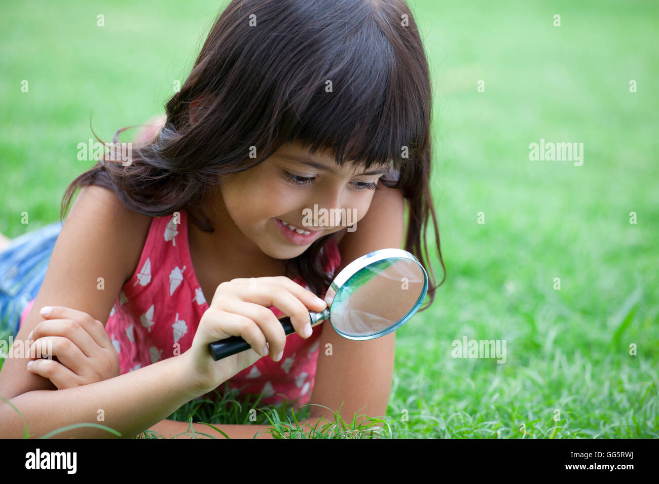 Smiling girl looking through magnifying glass Stock Photo - Alamy
