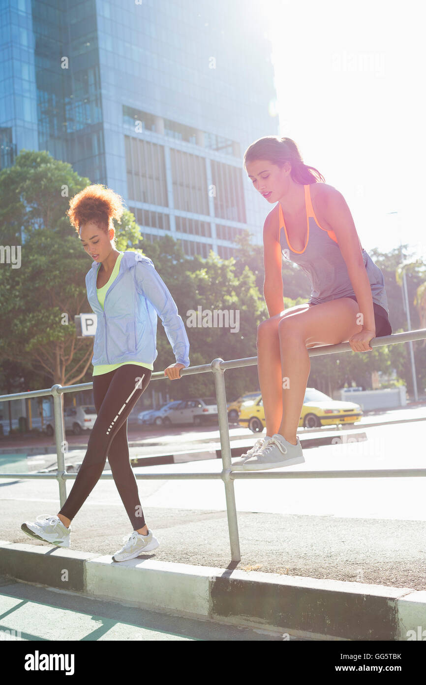Young female athletes taking a break during exercise by railings on ...