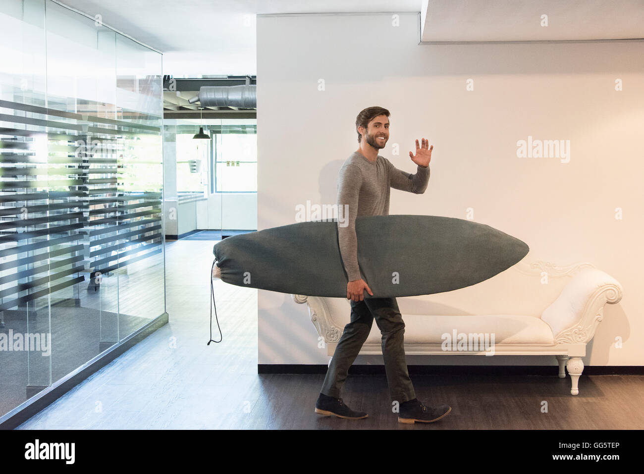 Happy young man carrying a surfboard at home Stock Photo - Alamy