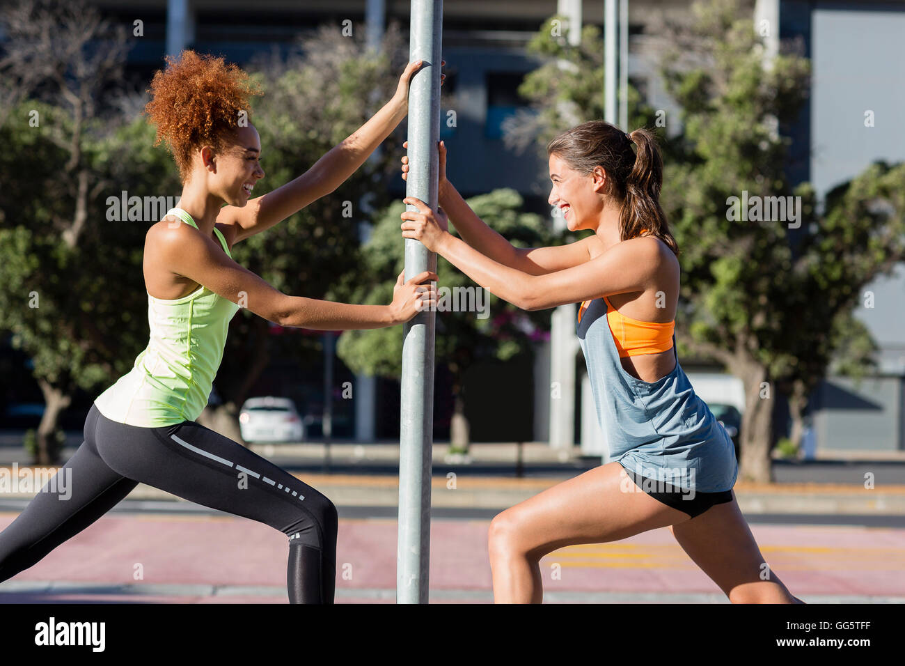 Young female athletes doing stretching exercise by pole on street Stock ...