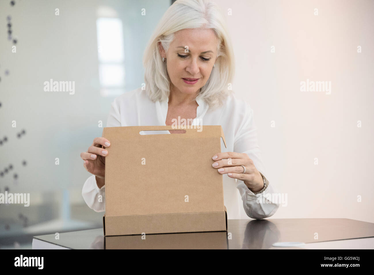 Mature woman opening a box at home Stock Photo - Alamy